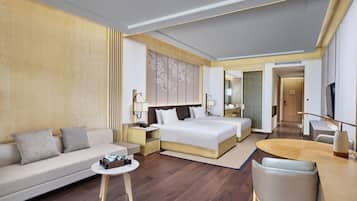 Quarto de hotel moderno com uma cama grande, um sofá, uma mesa de jantar e uma televisão.