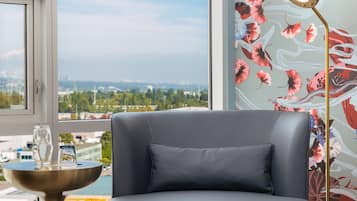 Uma sala de estar moderna com um sofá azul escuro, uma mesinha redonda com abajur e um papel de parede floral.