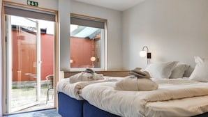 Quarto de hotel com cama, janela e porta para área externa.