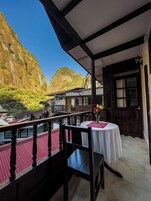 Varanda com mesa e cadeiras, vista para uma paisagem montanhosa.