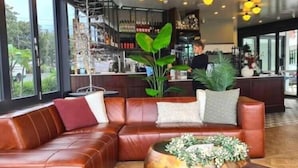 Uma área de estar moderna com um sofá de couro, uma mesa de centro com plantas e um bar ao fundo.