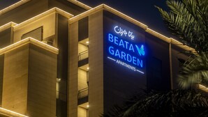 Um edifício moderno com uma placa luminosa que diz "Beata Garden Apartments".