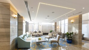 Um hall moderno com sofás, poltronas, uma mesa de centro e um vaso de planta.