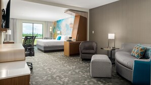 Quarto de hotel com cama, sofá, escrivaninha e cadeira.