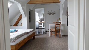 Quarto com cama, cadeira de madeira, escrivaninha e radiador.