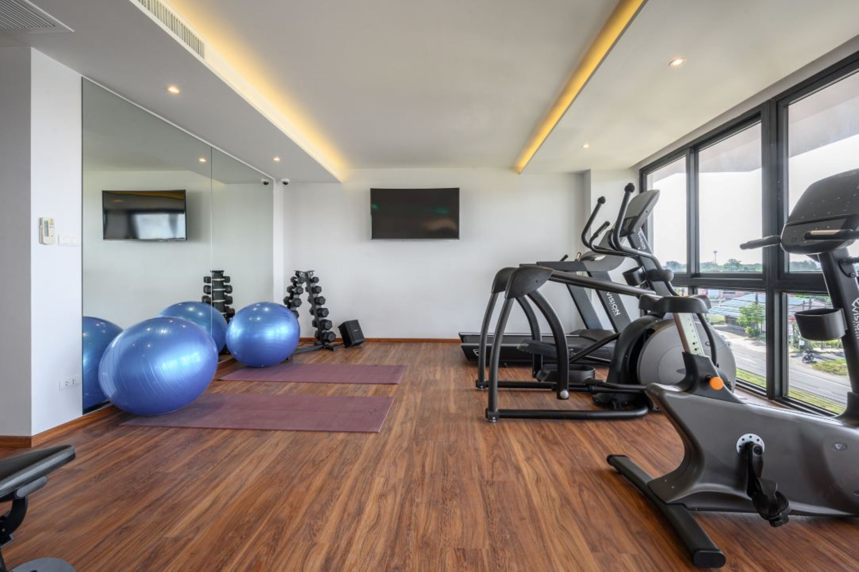 Uma academia moderna com equipamentos de ginástica, espelhos amplos e vista para o exterior.