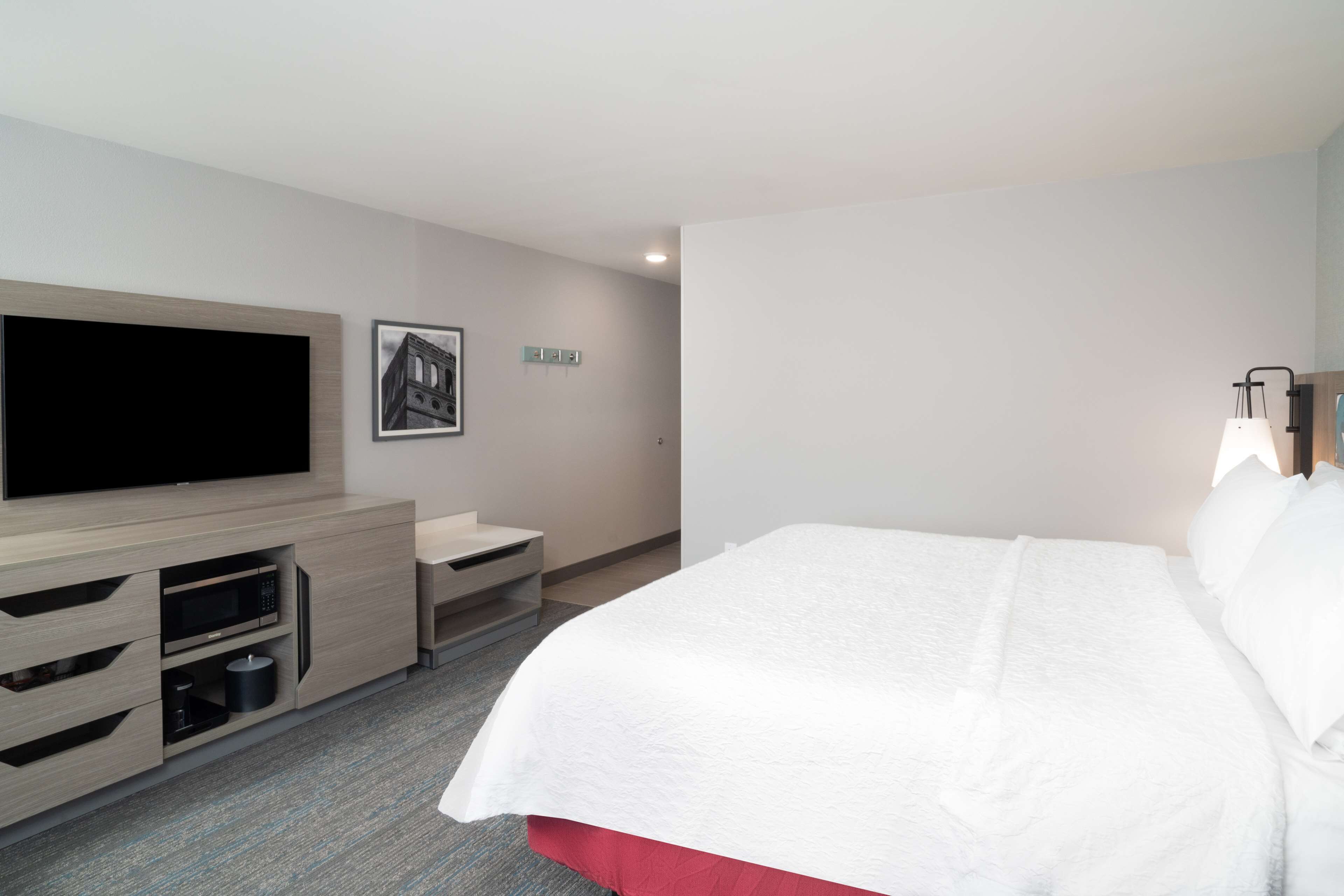 Quarto de hotel com uma cama grande, televisão de tela plana, micro-ondas e um pequeno espaço de estar.