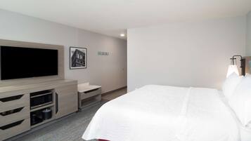 Quarto de hotel com uma cama grande, televisão de tela plana, micro-ondas e um pequeno espaço de estar.