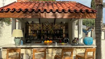 Uma área de bar com telhado de azulejos, paredes de pedra e cadeiras de madeira.