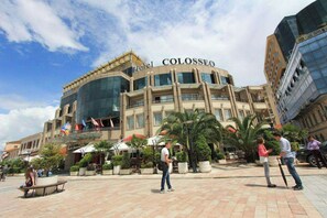 Hotel com fachada moderna, várias varandas e um pátio central com palmeiras e área de estar ao ar livre.