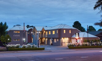 Hotel com design moderno, com vários pontos de entrada e fachada bem iluminada.