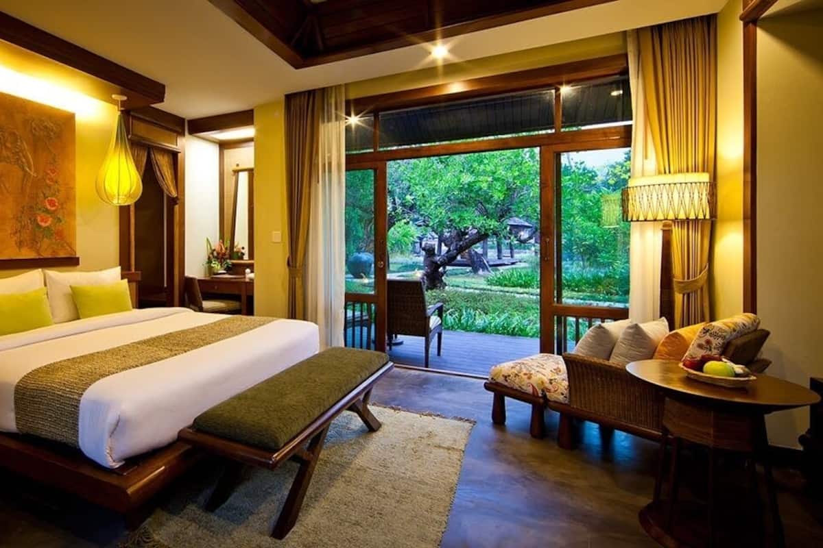 Quarto espaçoso com uma cama grande, um espaço de estar com uma mesa e vista para o exterior.