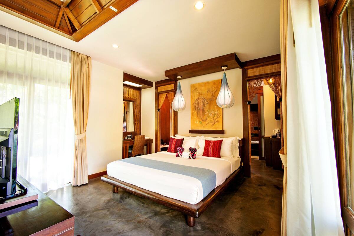 Quarto de hotel espaçoso com uma cama grande, televisão e teto de madeira.