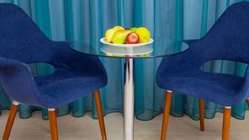 Duas cadeiras azuis ao redor de uma pequena mesa de vidro com um prato de frutas.