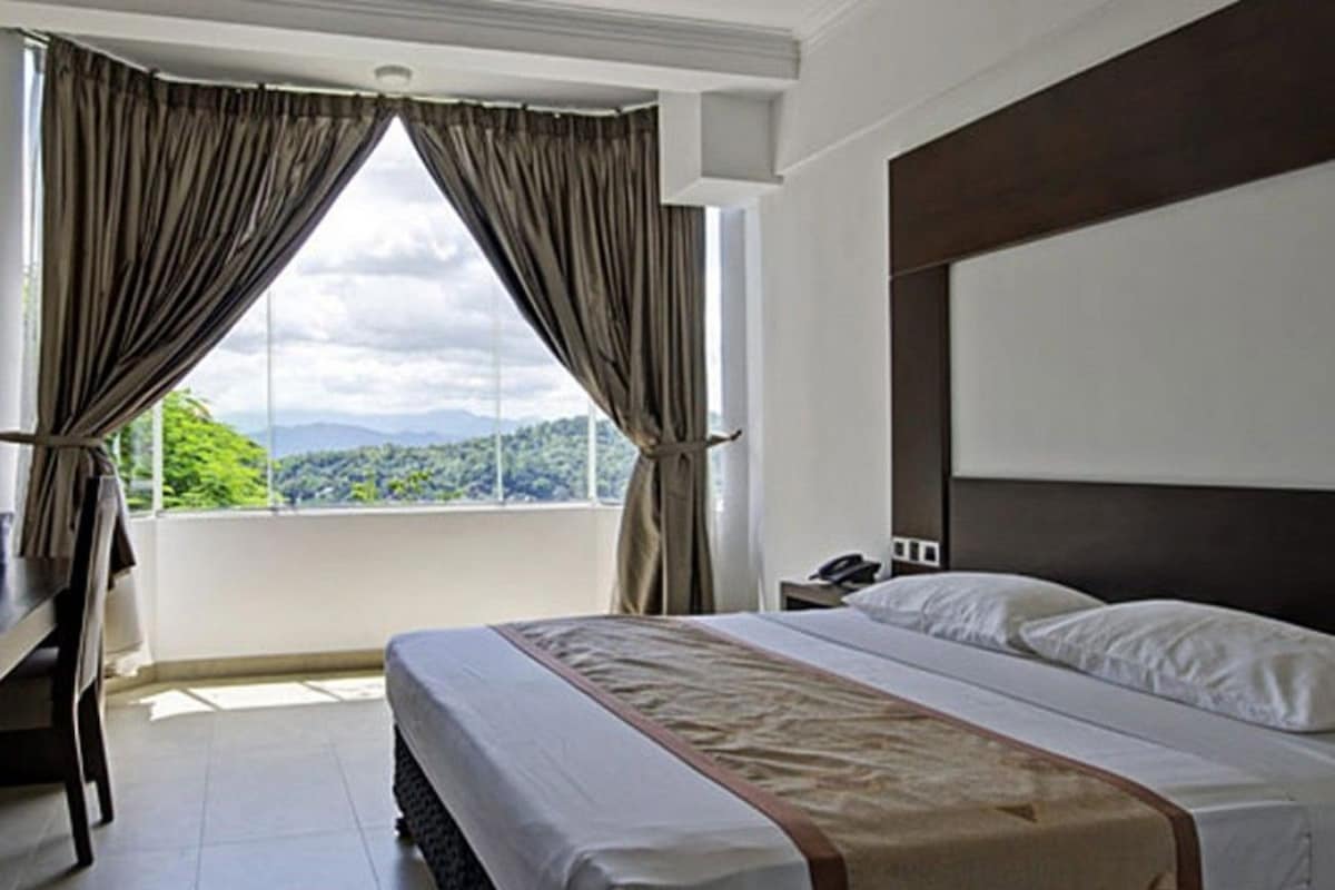 Quarto de hotel com cama, escrivaninha e vista para o exterior.