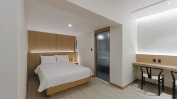 Quarto de hotel moderno com uma cama, uma escrivaninha e uma cadeira.