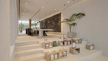 Interior moderno com escadaria que leva a uma área de recepção, apresentando uma parede de pedra, um balcão de recepção e um vaso de planta.
