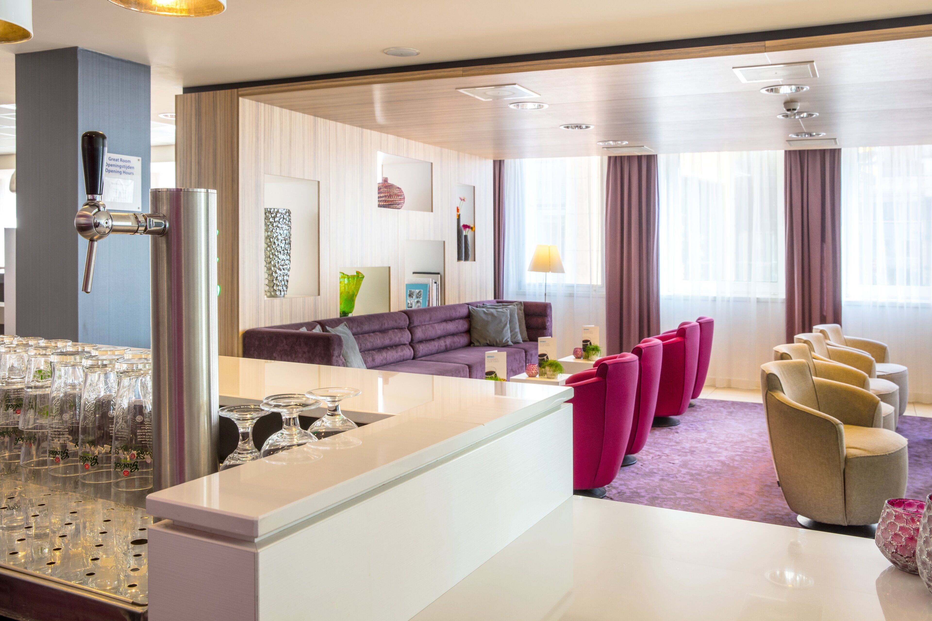 Quarto de hotel moderno com área de bar, espaço para sentar e vista para a cidade.