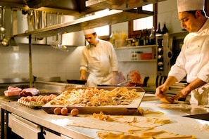 Um chef preparando comida em uma cozinha profissional, com diversos utensílios e ingredientes.