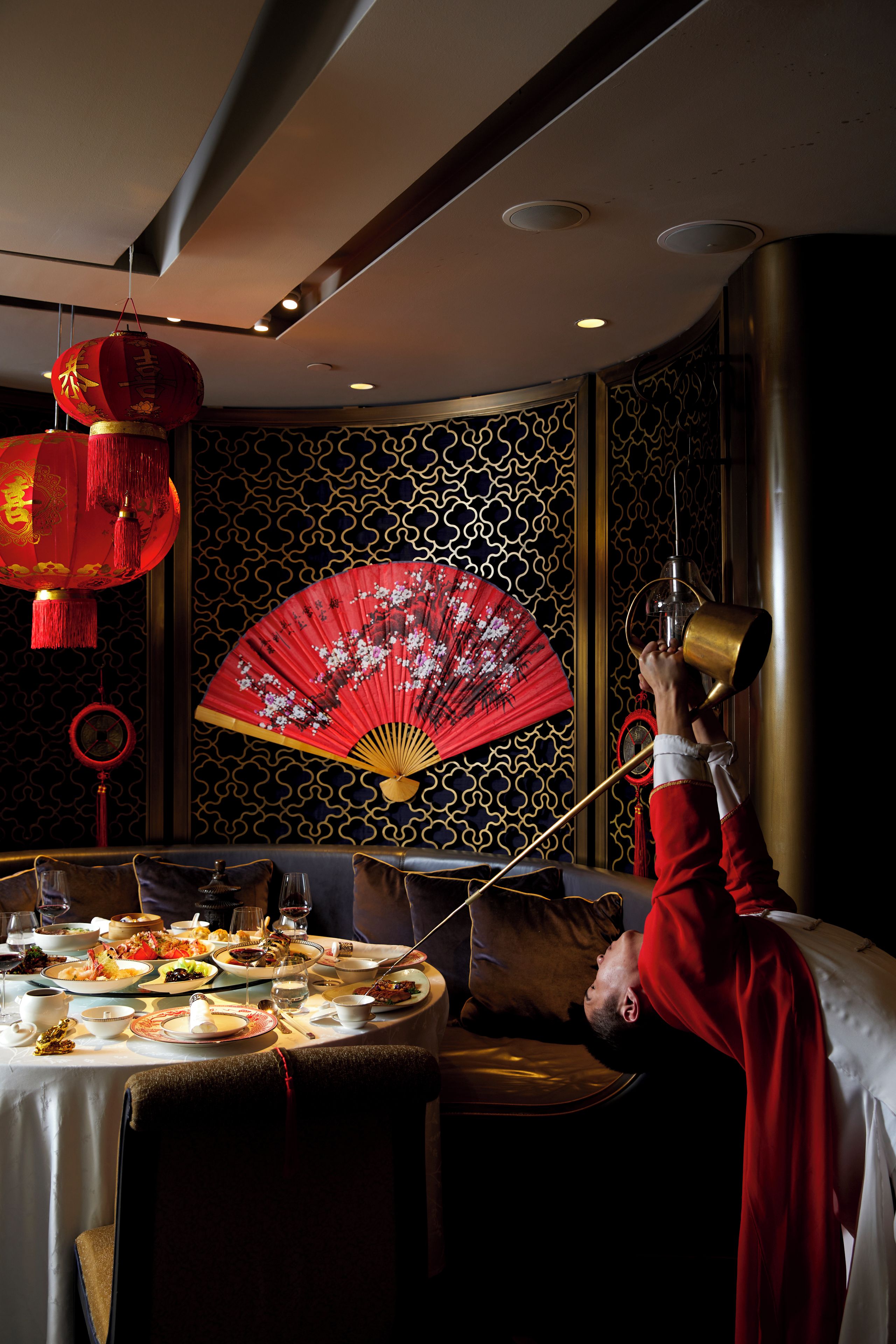 Uma área de refeições com mesa posta, um leque decorativo e lanternas chinesas tradicionais.