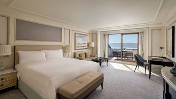 Quarto de hotel com cama grande, escrivaninha, cadeira, banco e varanda com vista.