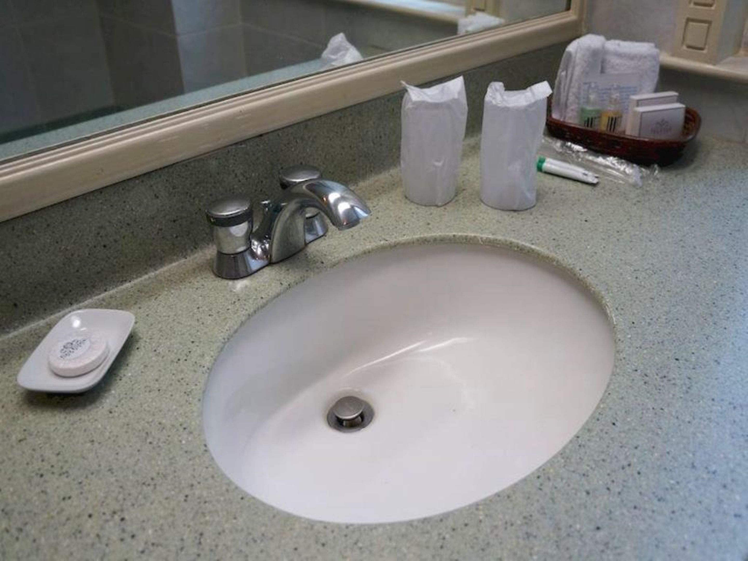 Uma pia de banheiro com um espelho acima, um porta-sabonete e artigos de higiene no balcão.