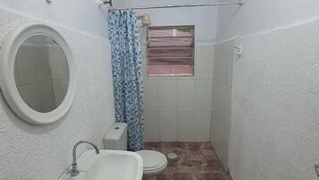 Uma casa de banho pequena com lavatório, sanita e janela com persianas.