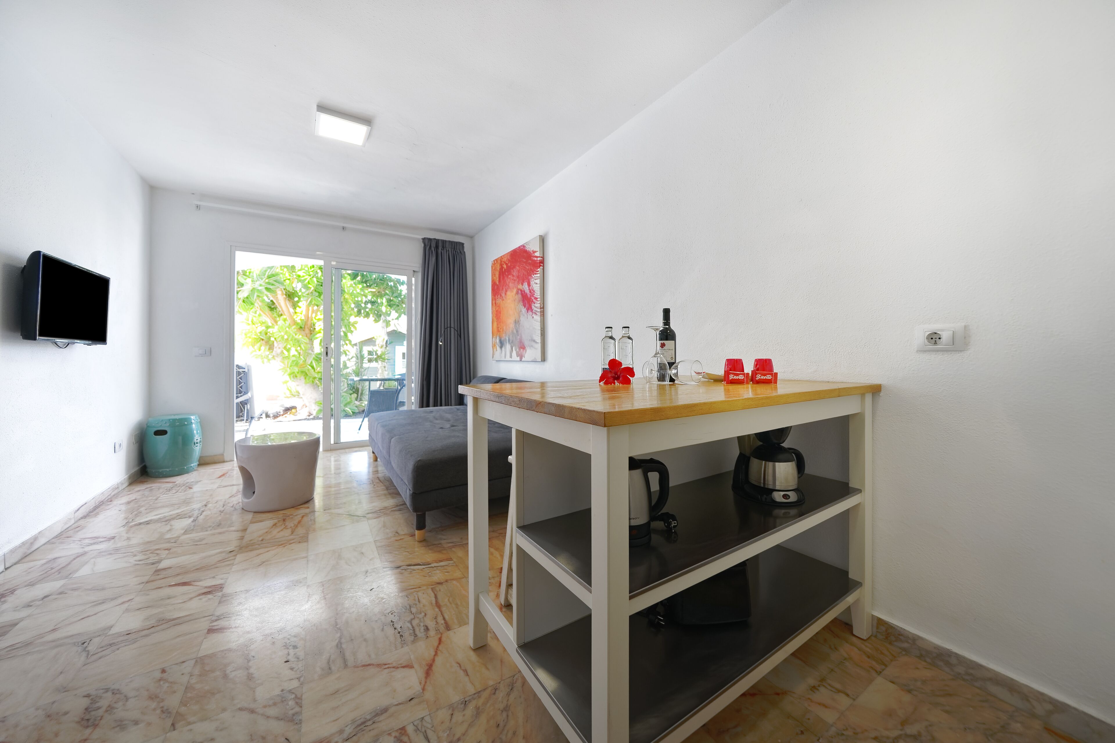 Cozinha moderna com uma mesa de madeira, uma cafeteira e uma TV fixada na parede.