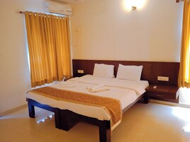 Quarto de hotel com cama, mesa de cabeceira, ar condicionado fixado na parede e cortinas.