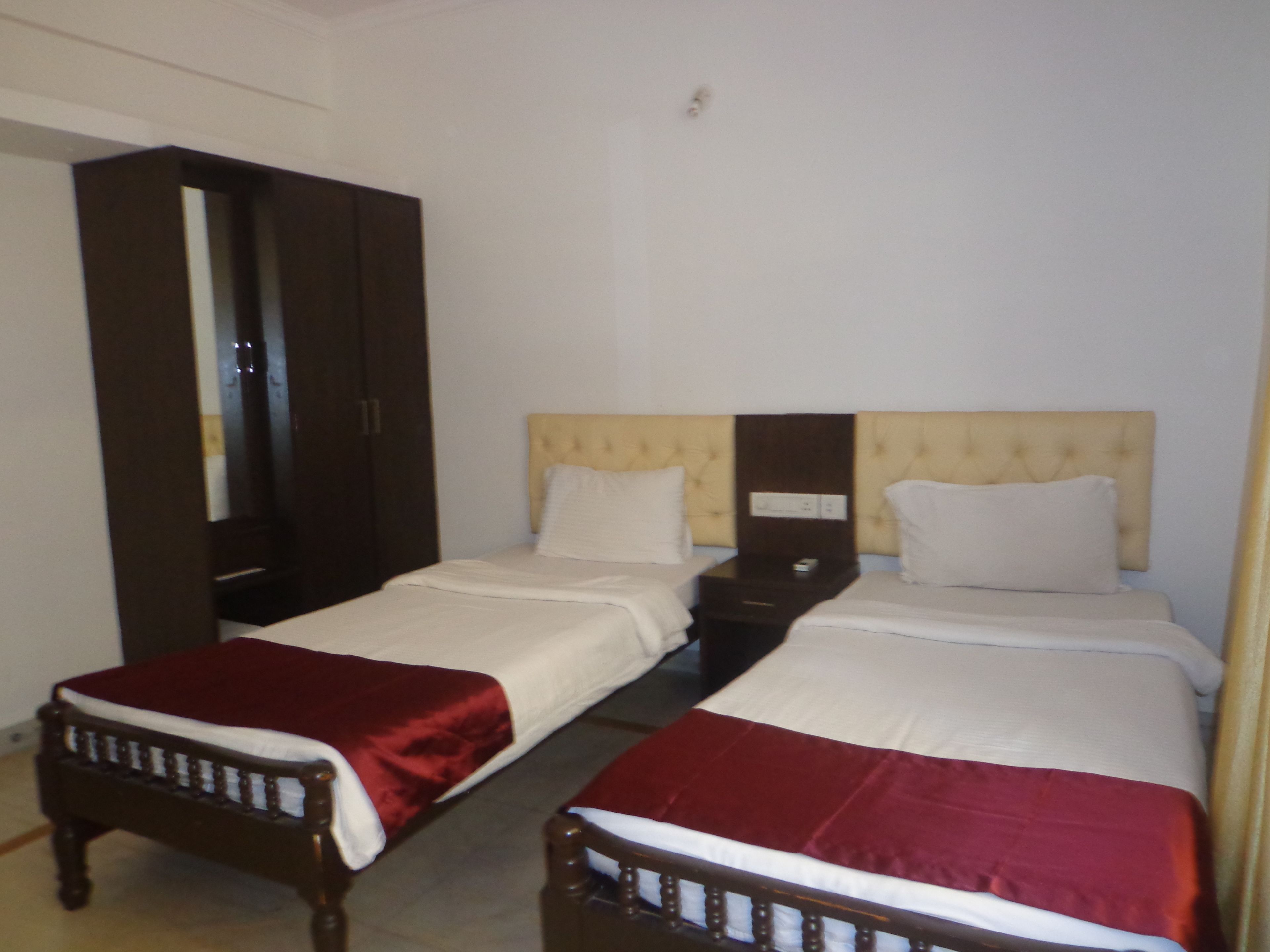 Quarto de hotel com duas camas de solteiro, um guarda-roupa e uma mesa de cabeceira.