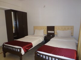 Quarto de hotel com duas camas de solteiro, um guarda-roupa e uma mesa de cabeceira.