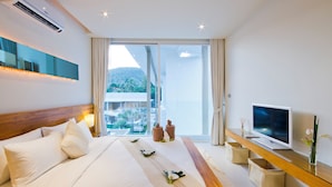 Quarto de hotel moderno com uma cama grande, uma TV de tela plana e vista para uma paisagem montanhosa através de uma porta de vidro deslizante.