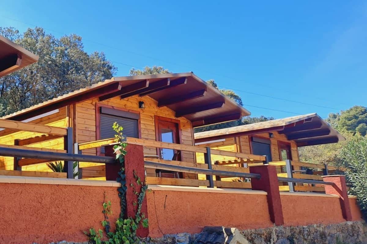 Uma cabana de madeira com varanda, alpendre coberto e parede externa vermelha.