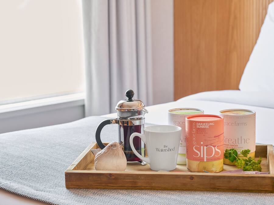 Uma bandeja com uma cafeteira, uma caneca e três velas sobre a cama.