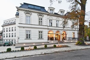 Um edifício branco com estilo arquitetônico clássico, apresentando uma entrada central com janelas em arco e uma placa com o dizeres 'Red Barn Inn'.
