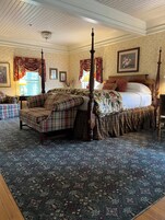 Um quarto tradicional com uma cama de dossel, um banco de madeira e um tapete estampado.