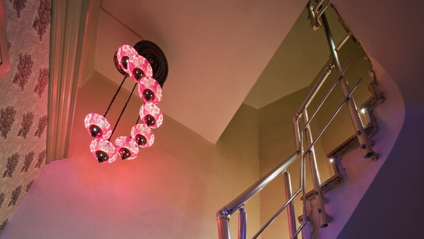 Uma escadaria com corrimão de metal e um candeeiro decorativo acima.