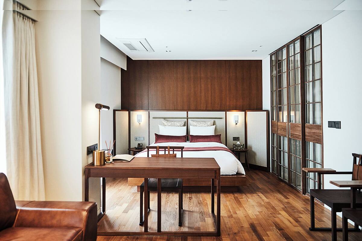 Quarto de hotel com uma cama grande, mesas de cabeceira, escrivaninha e mesa de jantar.