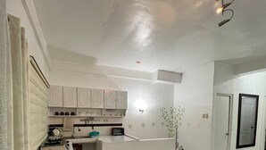 Uma cozinha moderna com armários brancos, uma ilha integrada e uma geladeira.