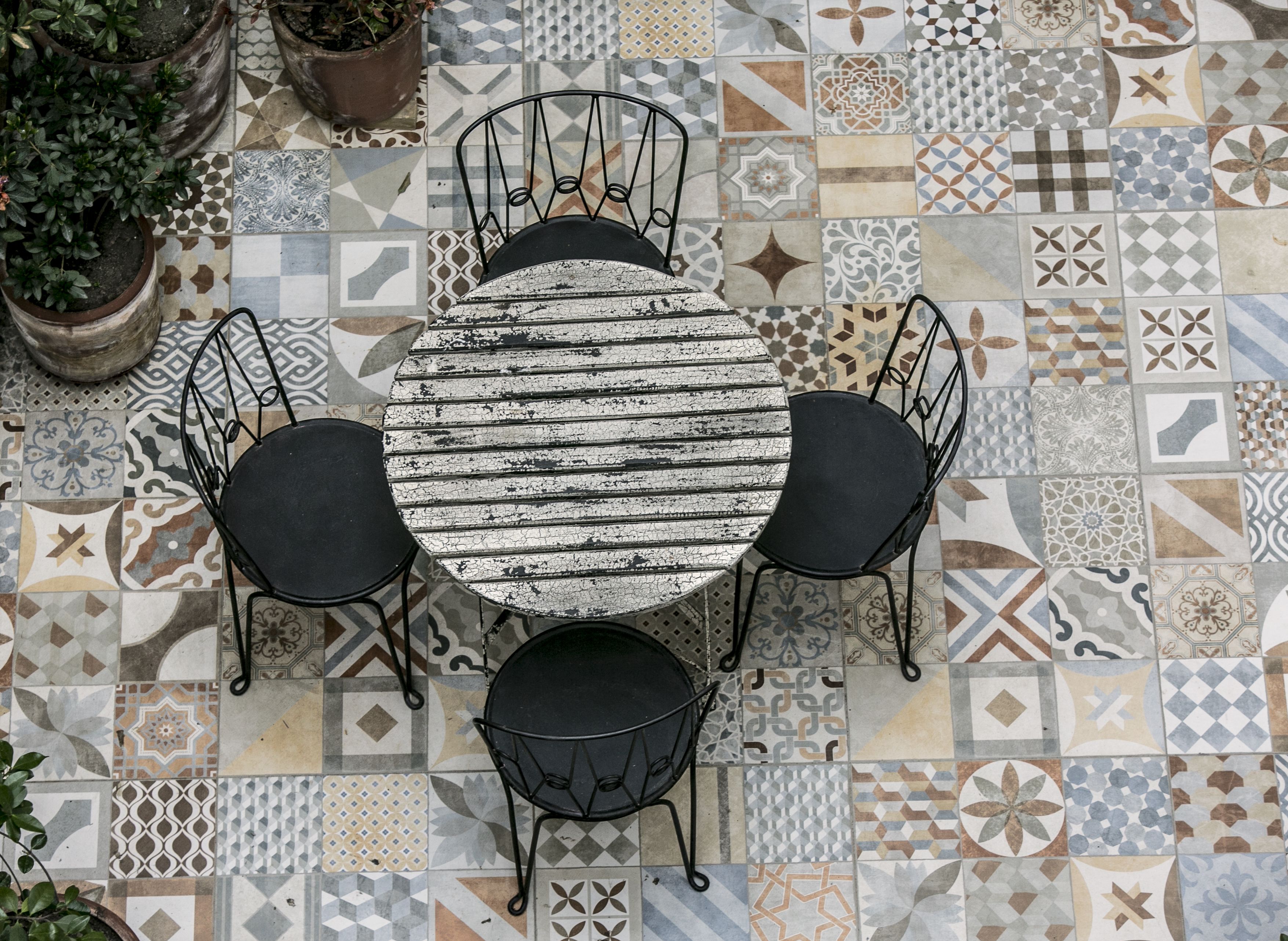 Uma mesa redonda com quatro cadeiras, rodeada por diversos azulejos estampados.