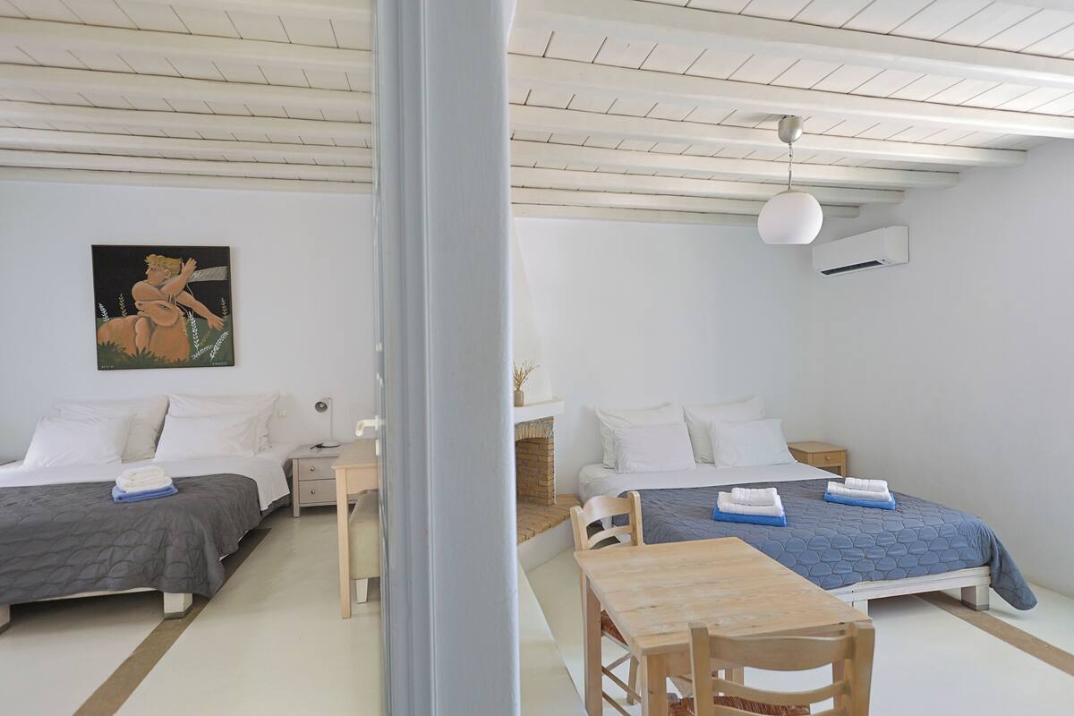 Quarto com duas camas, uma mesa de madeira e um quadro na parede.