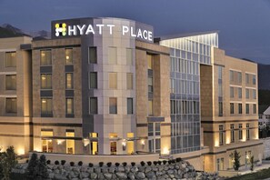 Um hotel moderno Hyatt Place com uma placa de destaque, vários andares e fachada de pedra.