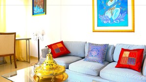 Um quarto com sofá, almofadas, mesa e um quadro na parede.