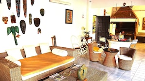 Uma sala de estar ampla com um sofá, cadeiras de vime e uma mesa de centro.
