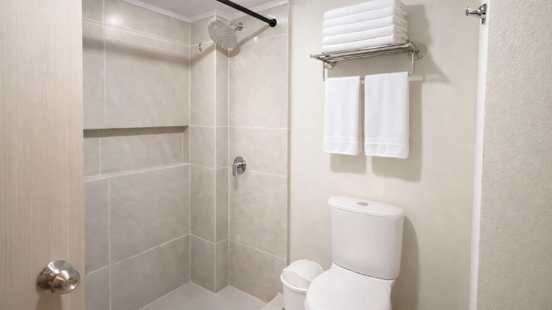 Uma casa de banho moderna com chuveiro, sanita e porta-toalhas.