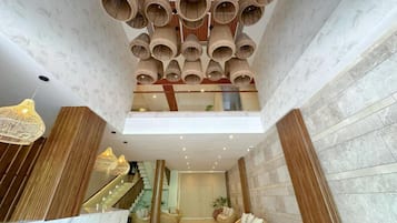Um hall amplo com teto alto, escadaria e balcão de recepção.