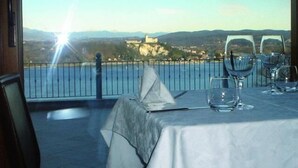 Mesa posta para dois, com vista para a paisagem costeira e um castelo.