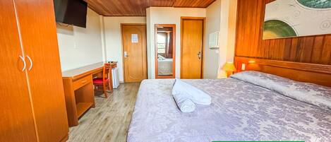 Um quarto com cama, escrivaninha e guarda-roupa.