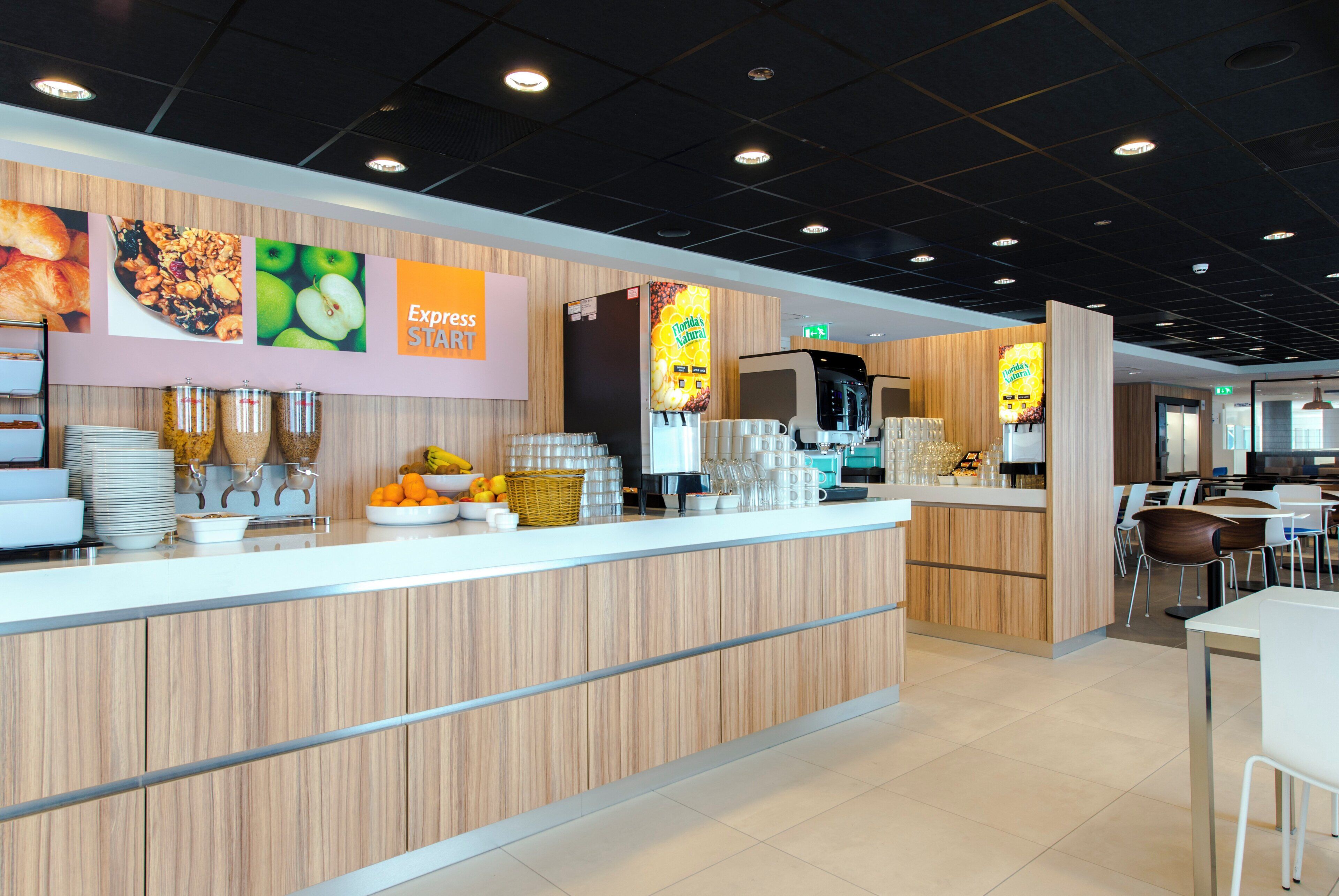 Um café moderno com balcão de madeira, diversos displays de comida e áreas de estar.