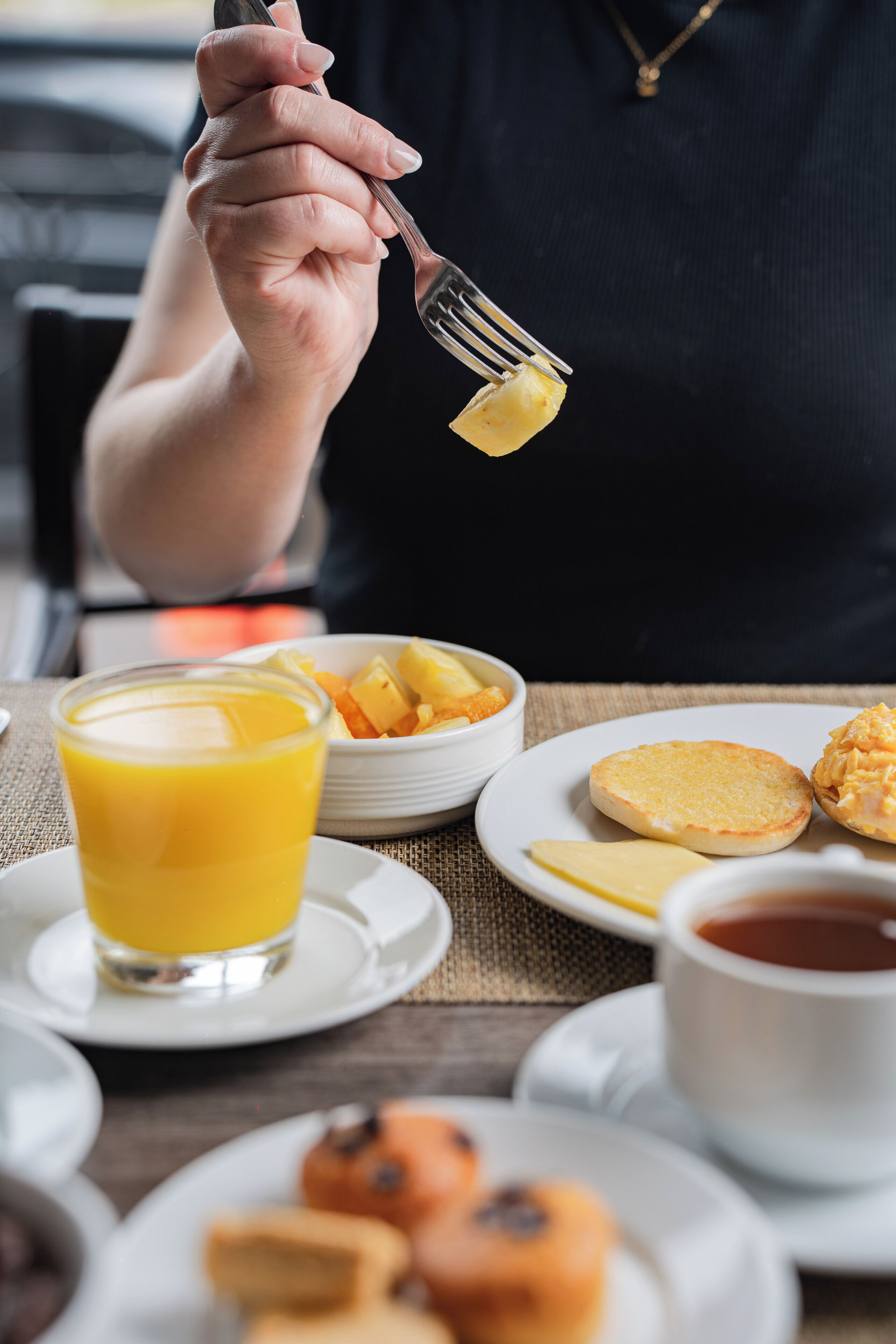 Uma mesa de café da manhã com torradas, um copo de suco de laranja e uma tigela de frutas.